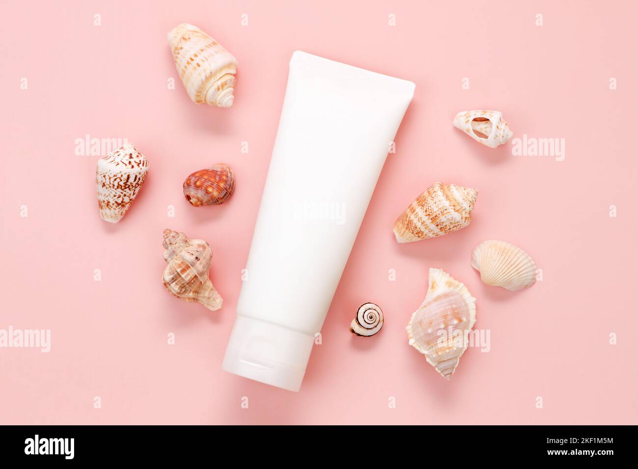 Mockup white squeeze bottle cosmetic tube and sea shells a lot on pink ...