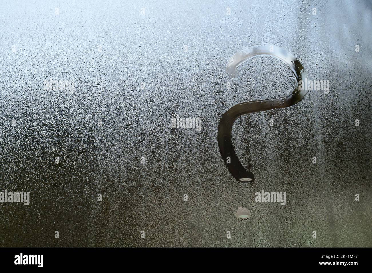 A question mark is drawn on glass with condensation, the effect of ...