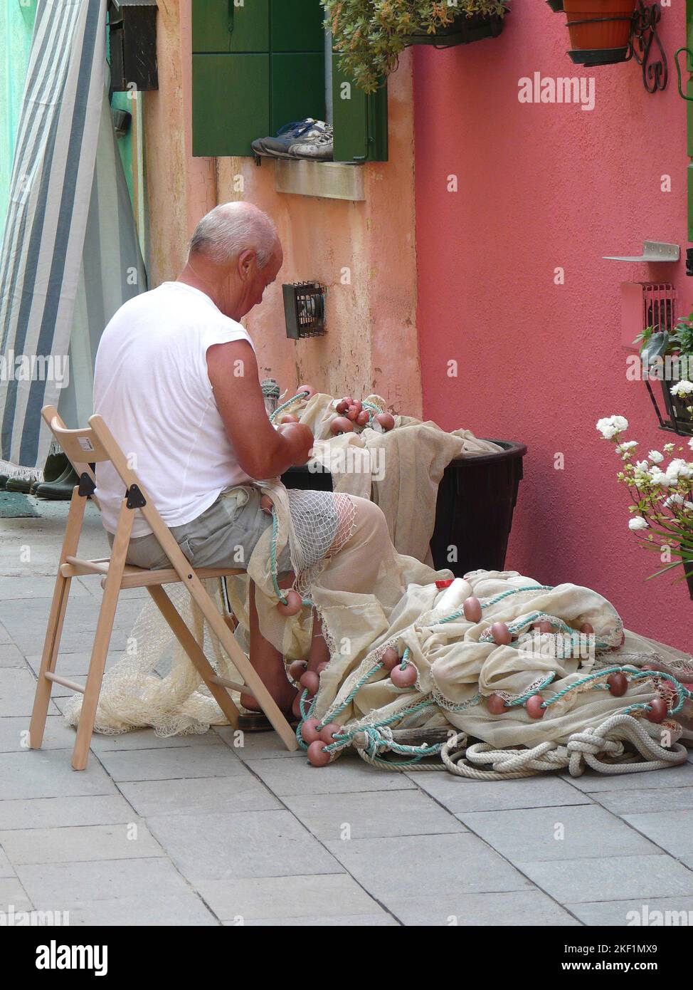 A fisherman on Burano is patching his fishing net Stock Photo - Alamy