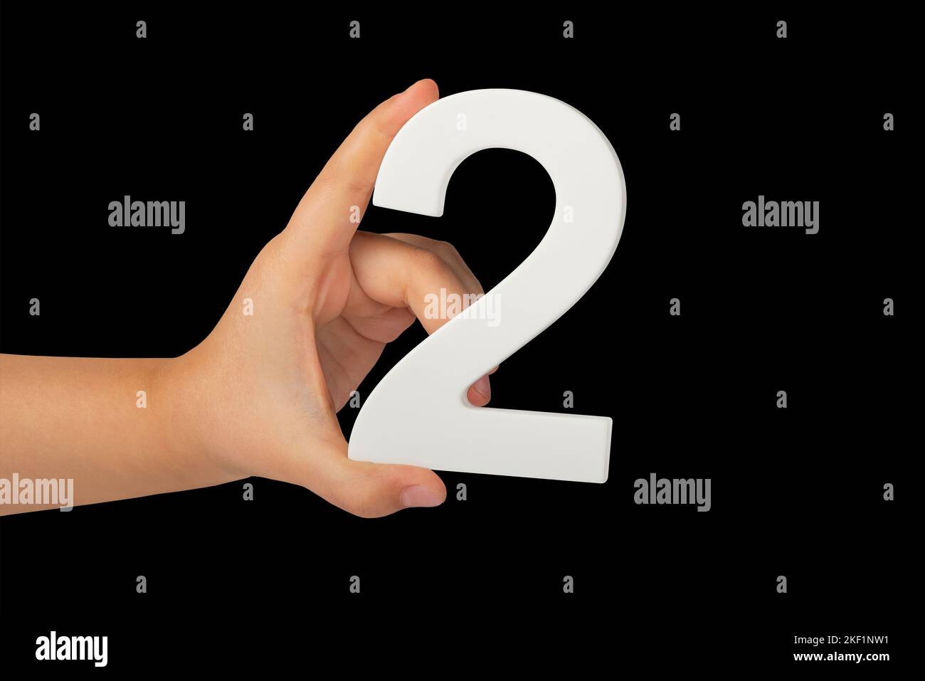 Close-up hand holding a white number 2 on a black background. Number ...