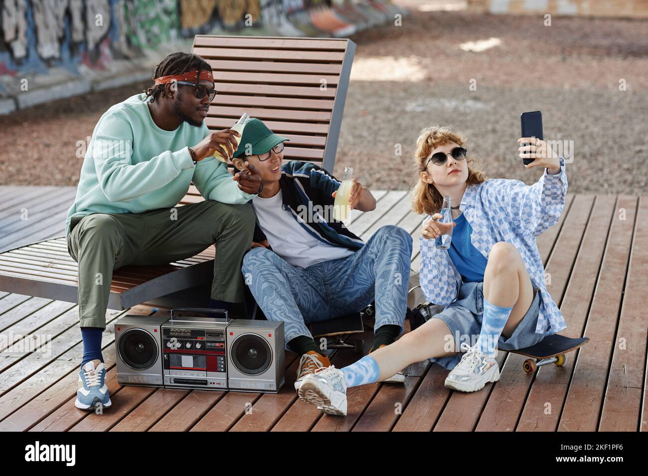 Diverse group of young people hanging out outdoors with boombox and ...