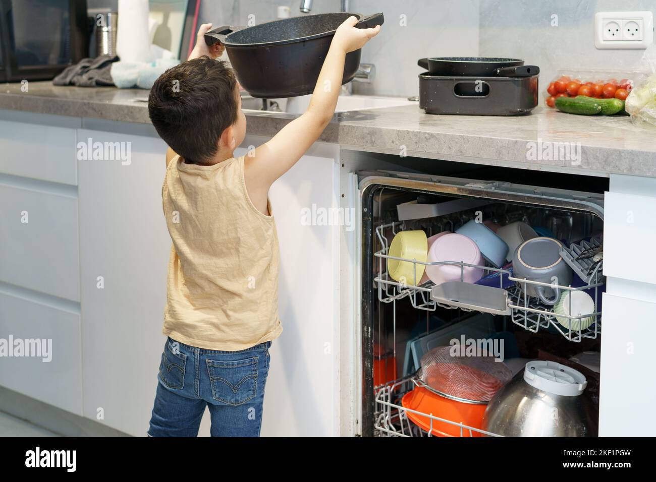 Little child participates in tasks and chores, unloading dishwasher ...