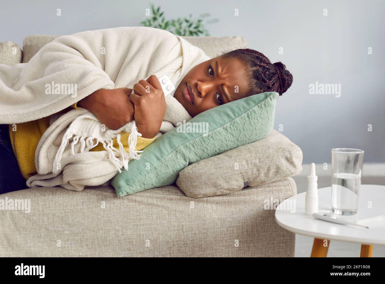 Sick young woman lying on coach suffering from flu symptoms Stock Photo ...