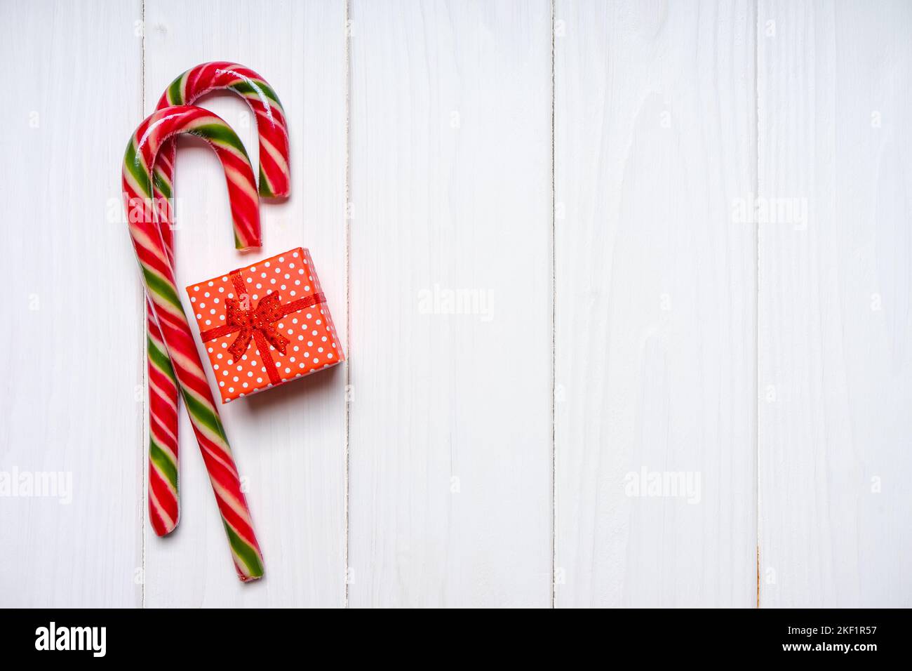 Christmas candy cane and red gift box on white wooden background. Flat ...