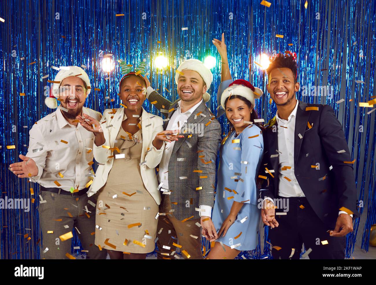 Colleagues are having fun together under falling confetti celebrating ...