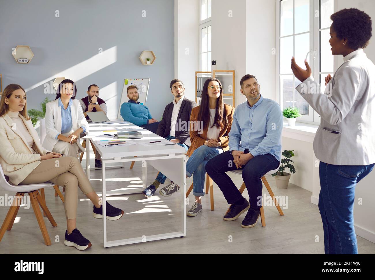 Team of business people listen to colleague during meeting about ...