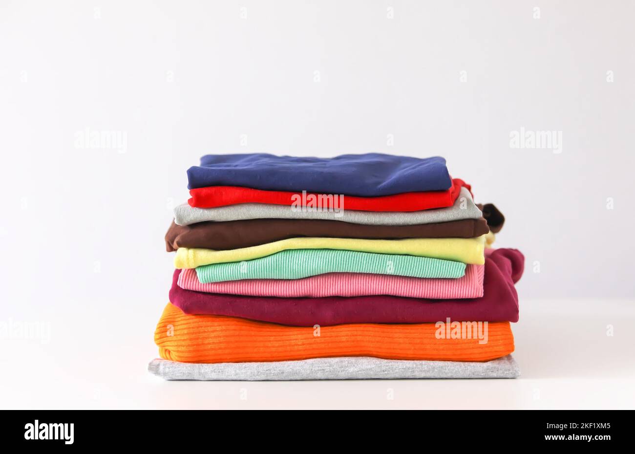 Stack of folded colorful clothes. Compact storage organizing in home ...