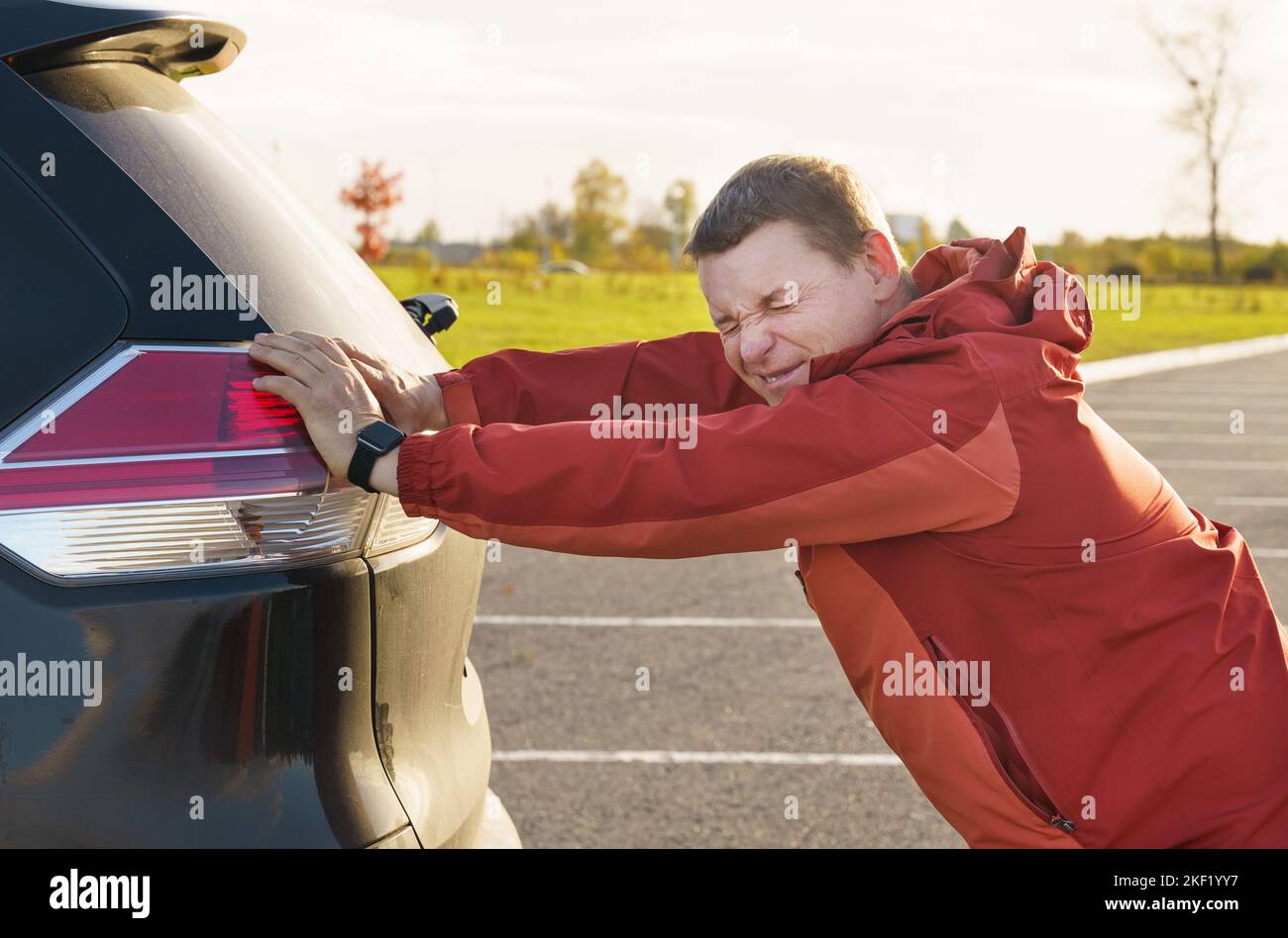 A man pushes his broken car to a parking lot. Transport concept Stock ...