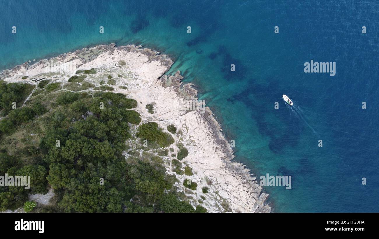 An aerial drone view of a boat speeding in a sea with crystal azure ...