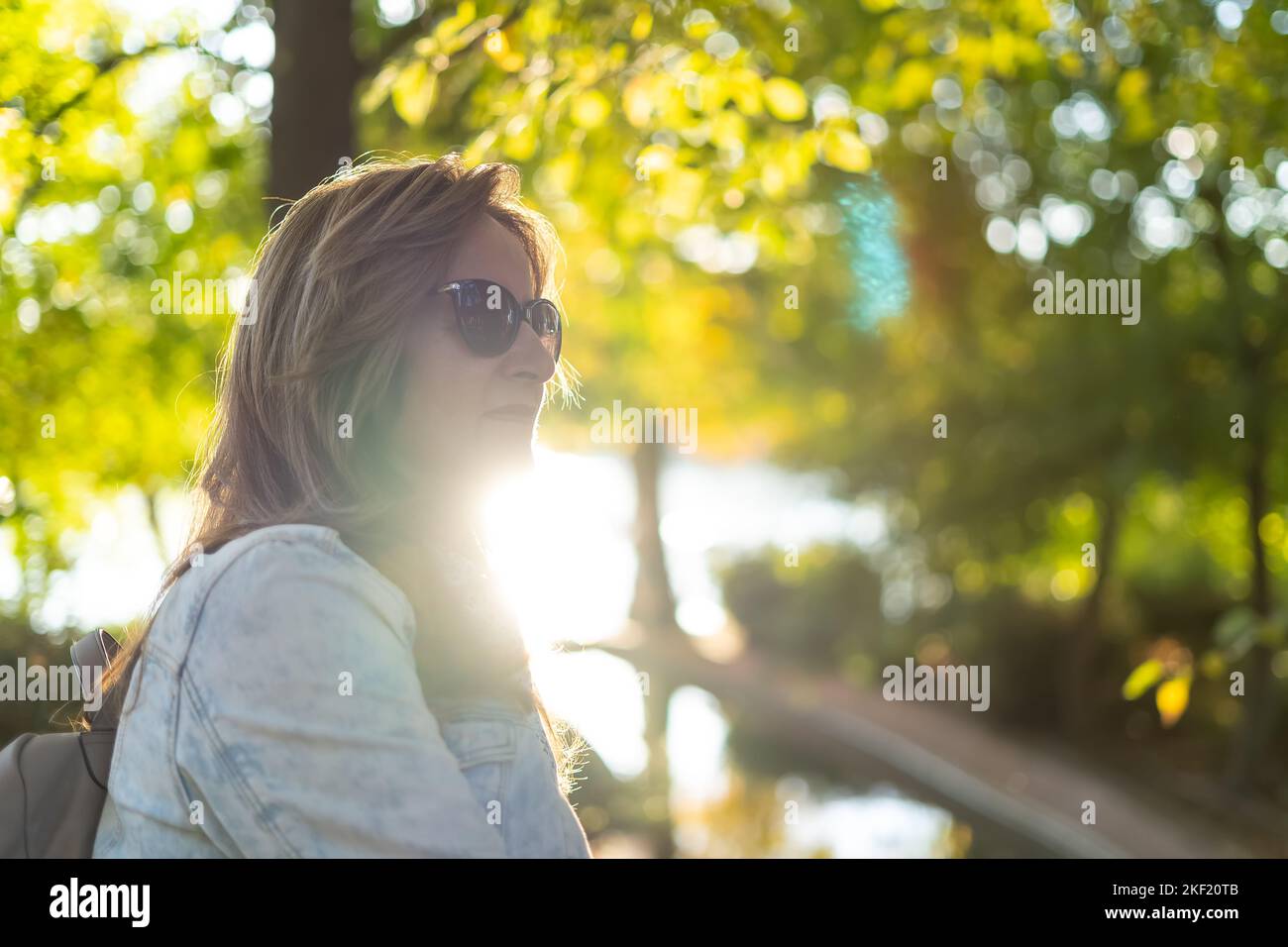 White woman in a backlit portrait with the autumn sun warming from ...