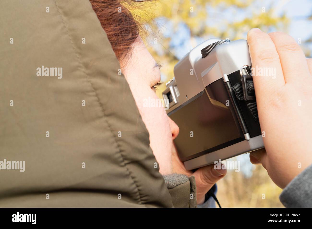 Side view photo of a photographer woman outdoors holding camera close ...
