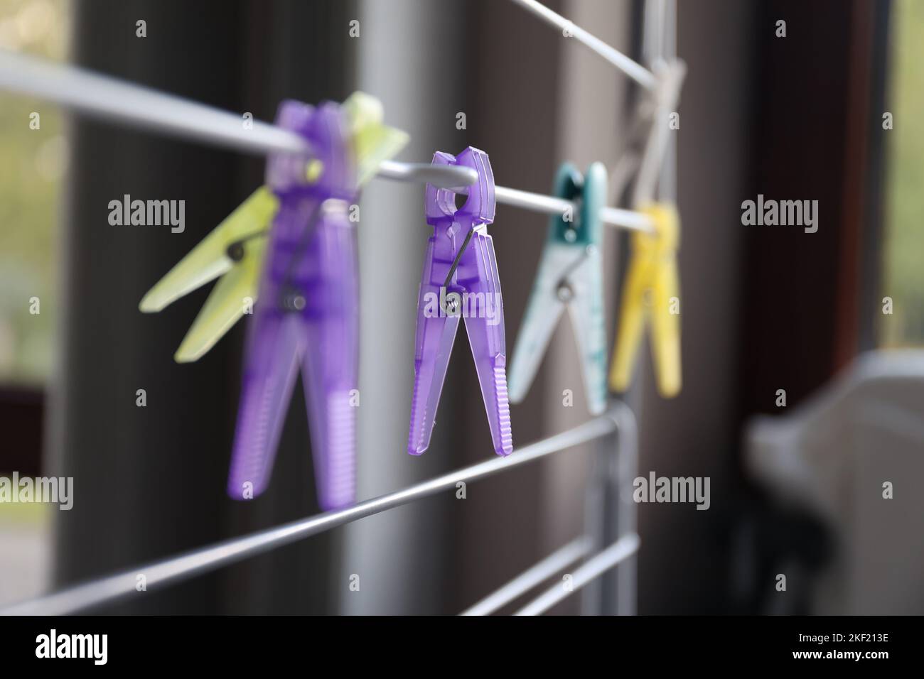 a portrait of a purple washingpin hanging on a washing rack inbetween ...