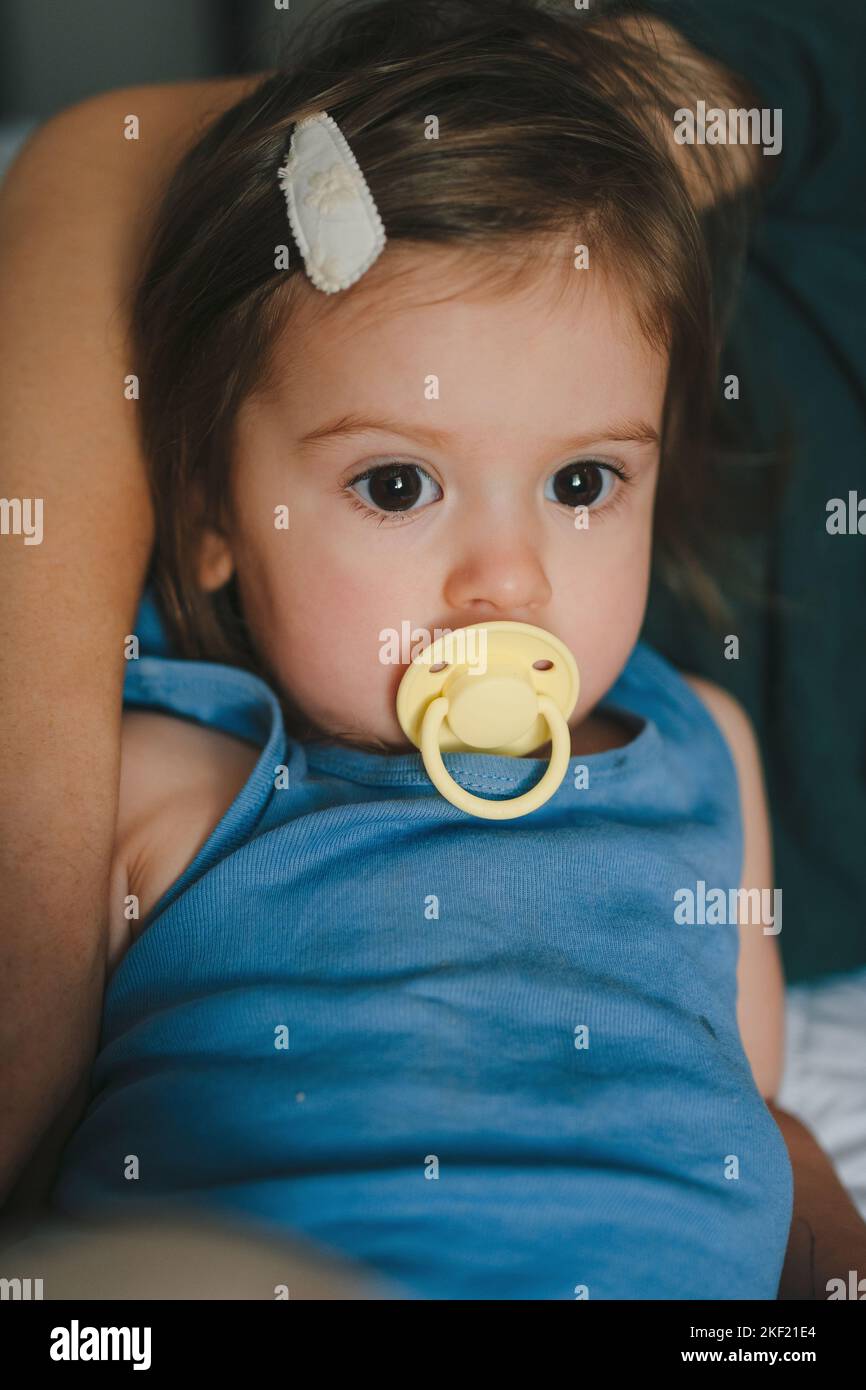 Close-up portrait of a baby girl lying down next to her mother while ...