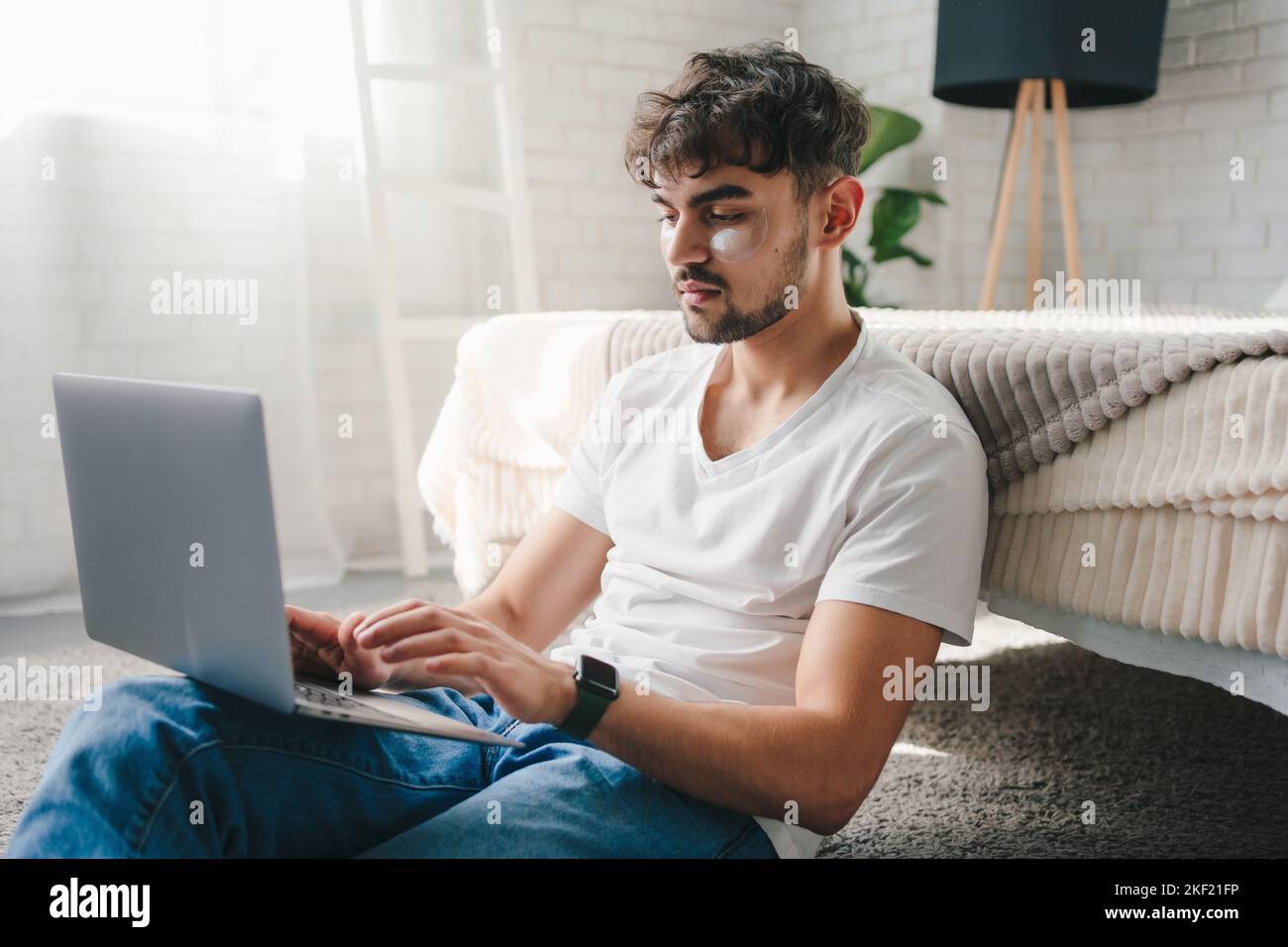 Calm man relaxing with laptop sitting on the floor, enjoying lazy ...