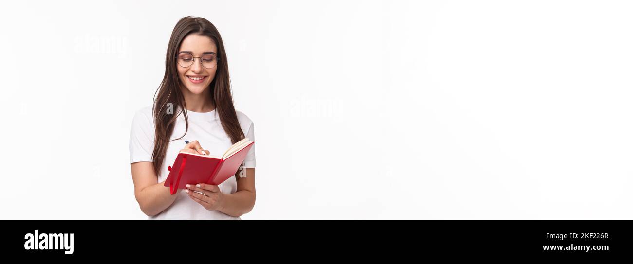 Portrait of smiling pretty caucasian girl writing in her diary, prepare ...