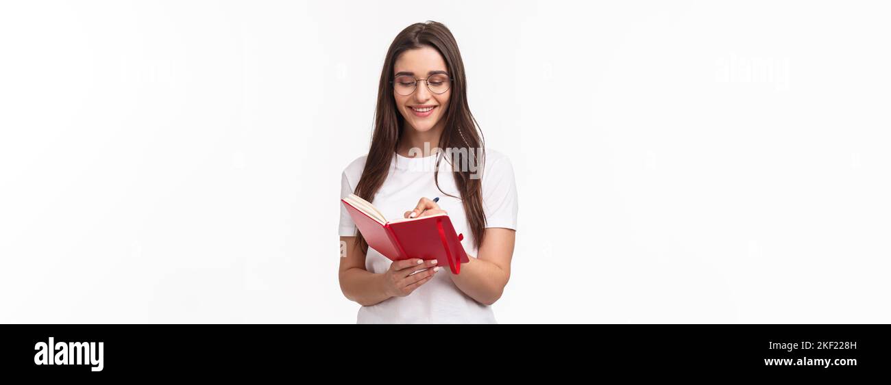 Portrait of smiling pretty caucasian girl writing in her diary, prepare ...