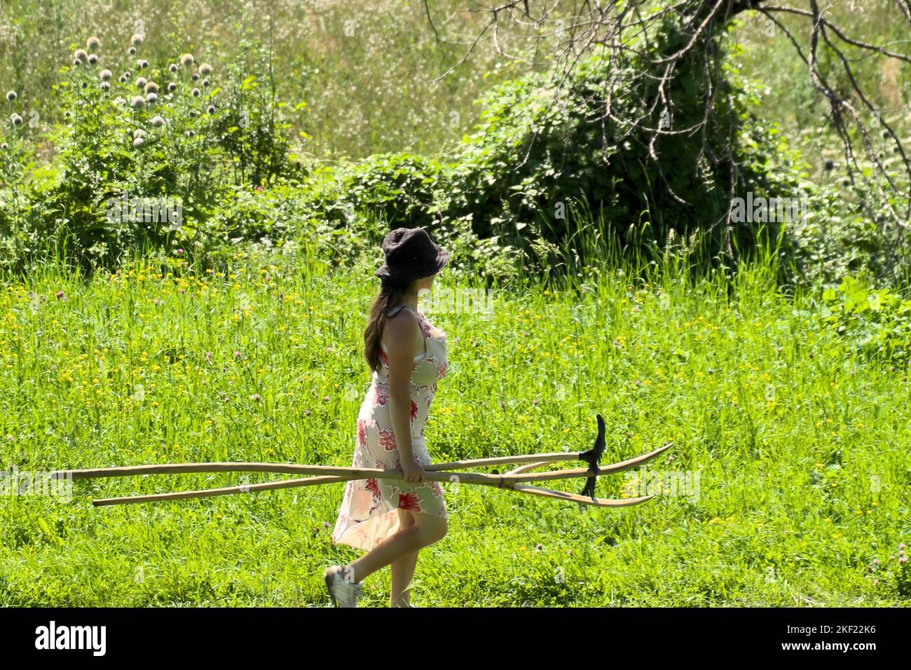 young woman in field carrying farm tools wearing unusual clothes Stock ...