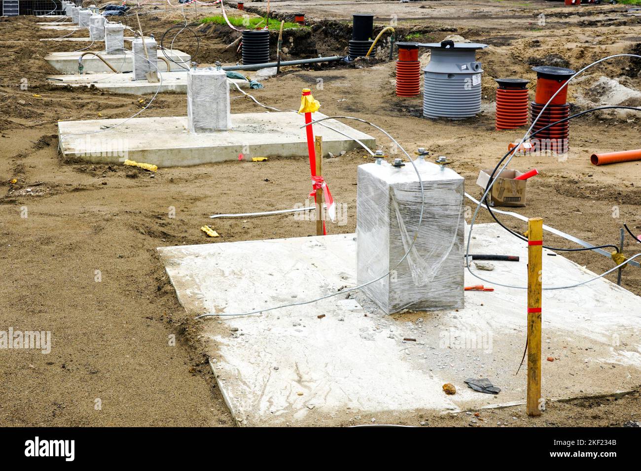 Row of concrete footings for steel columns, installation of plastic ...
