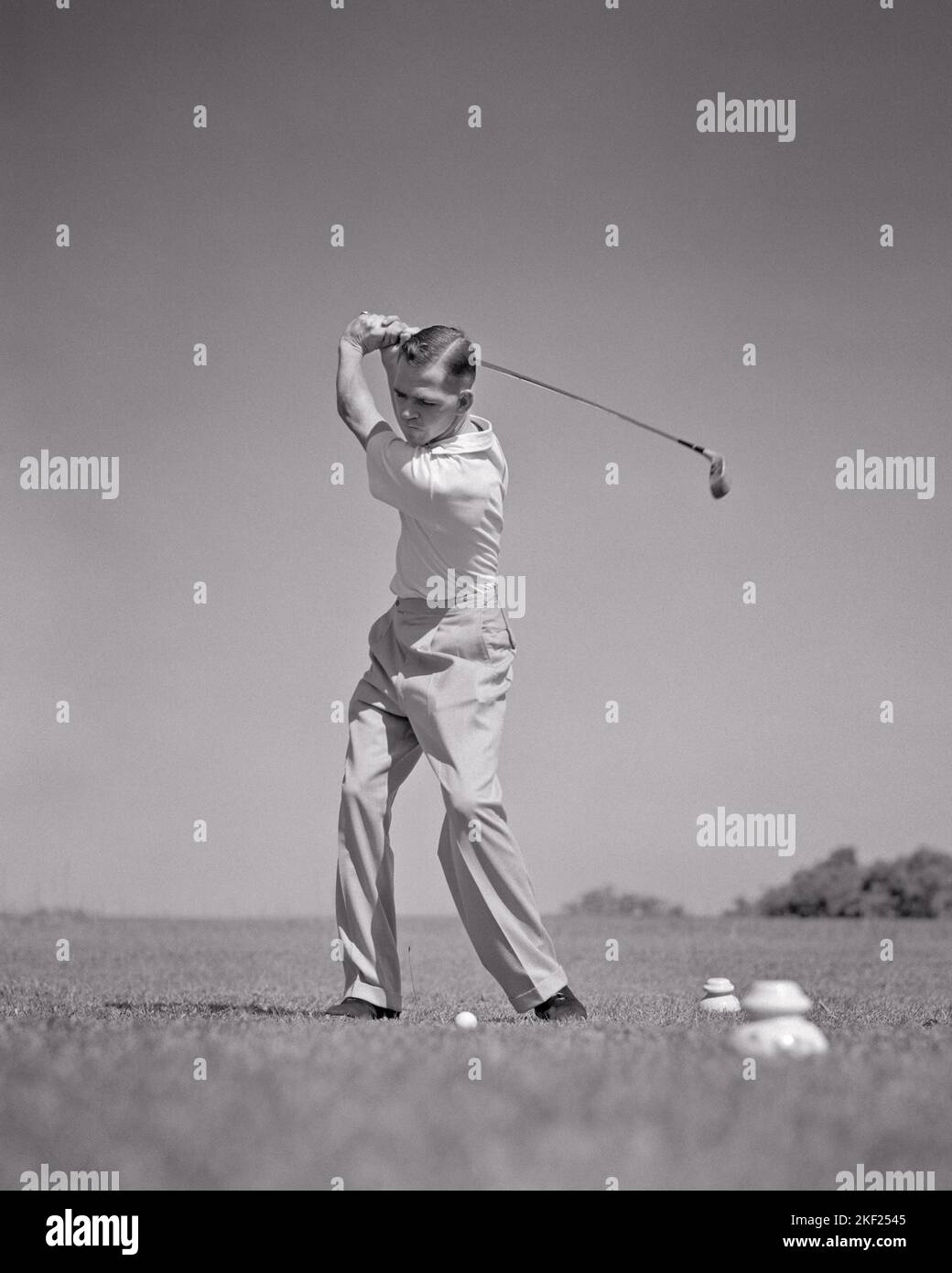 1950s 1960s MAN GOLFER WITH HIS CLUB AT THE TOP OF HIS SWING TEEING OFF ...