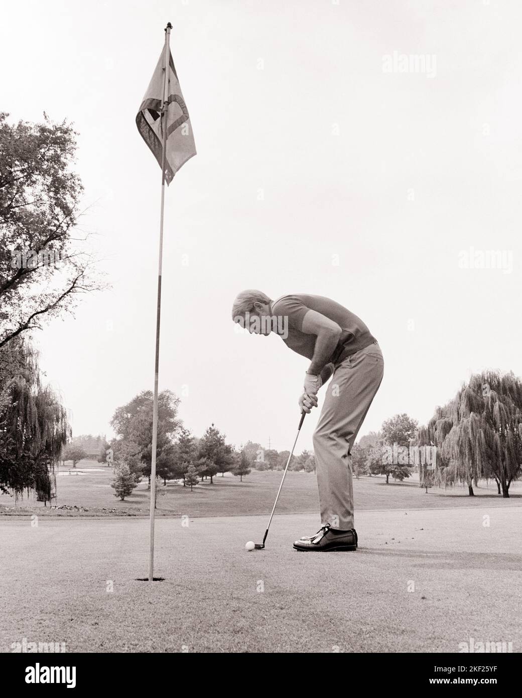 1960s 1970s GOLFER CROUCHED OVER BALL WITH PUTTER ON GREEN PUTTING FOR ...