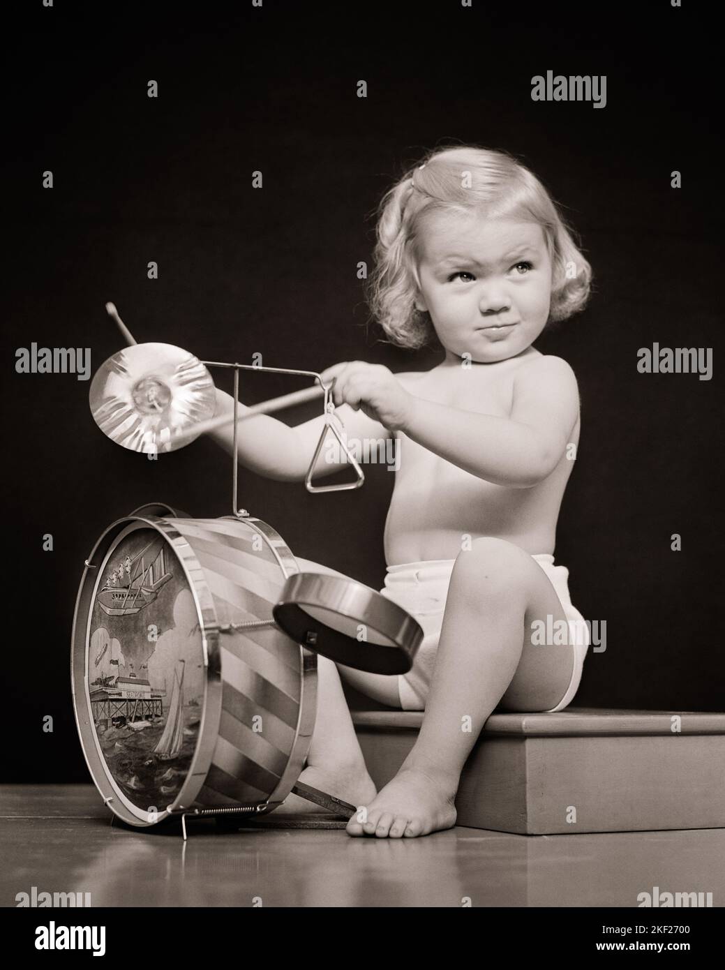 1940s LITTLE BLONDE GIRL SEATED AT DRUM SET STRIKING THE CYMBAL LOOKING ...