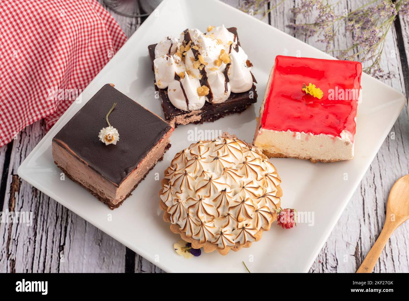 A white square plate with mini sweet cakes on a wooden table Stock ...