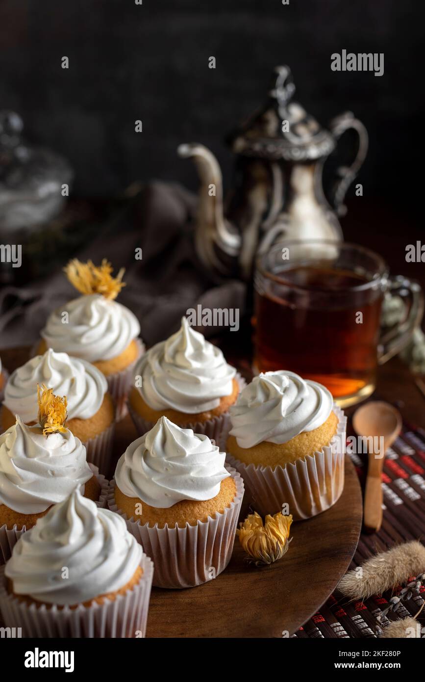 A closeup of muffins with meringue and cream on top on a wooden table ...