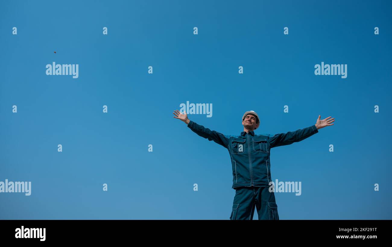 A caucasian man in work clothes and a construction helmet stands ...