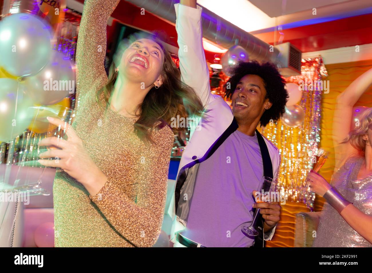 Happy diverse couple dancing and drinking champagne at a nightclub ...