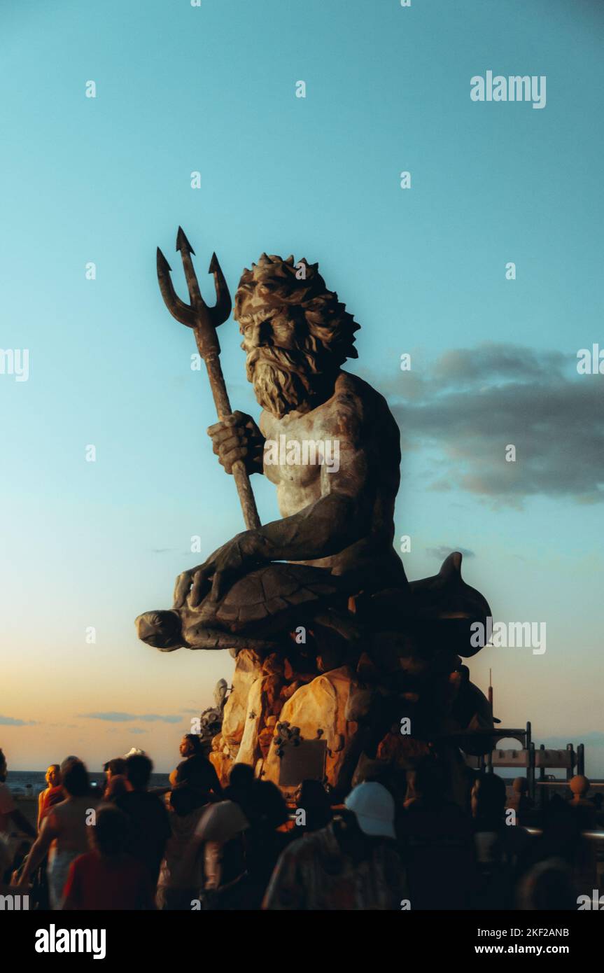 A giant stone sculpture of Neptune holding a sea turtle, surrounded by ...