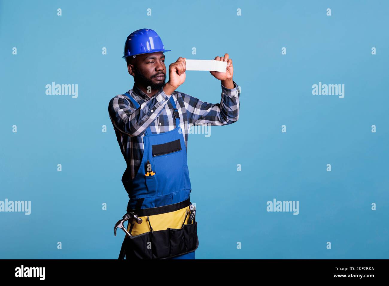 Professional house painter looks at masking tape to calculate the ...