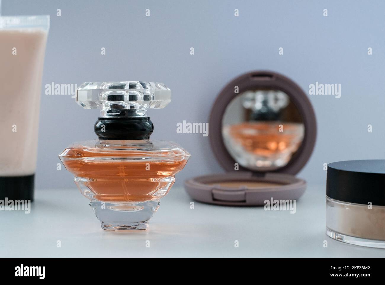 A perfume bottle surrounded by beauty products, powder, lotion Stock ...