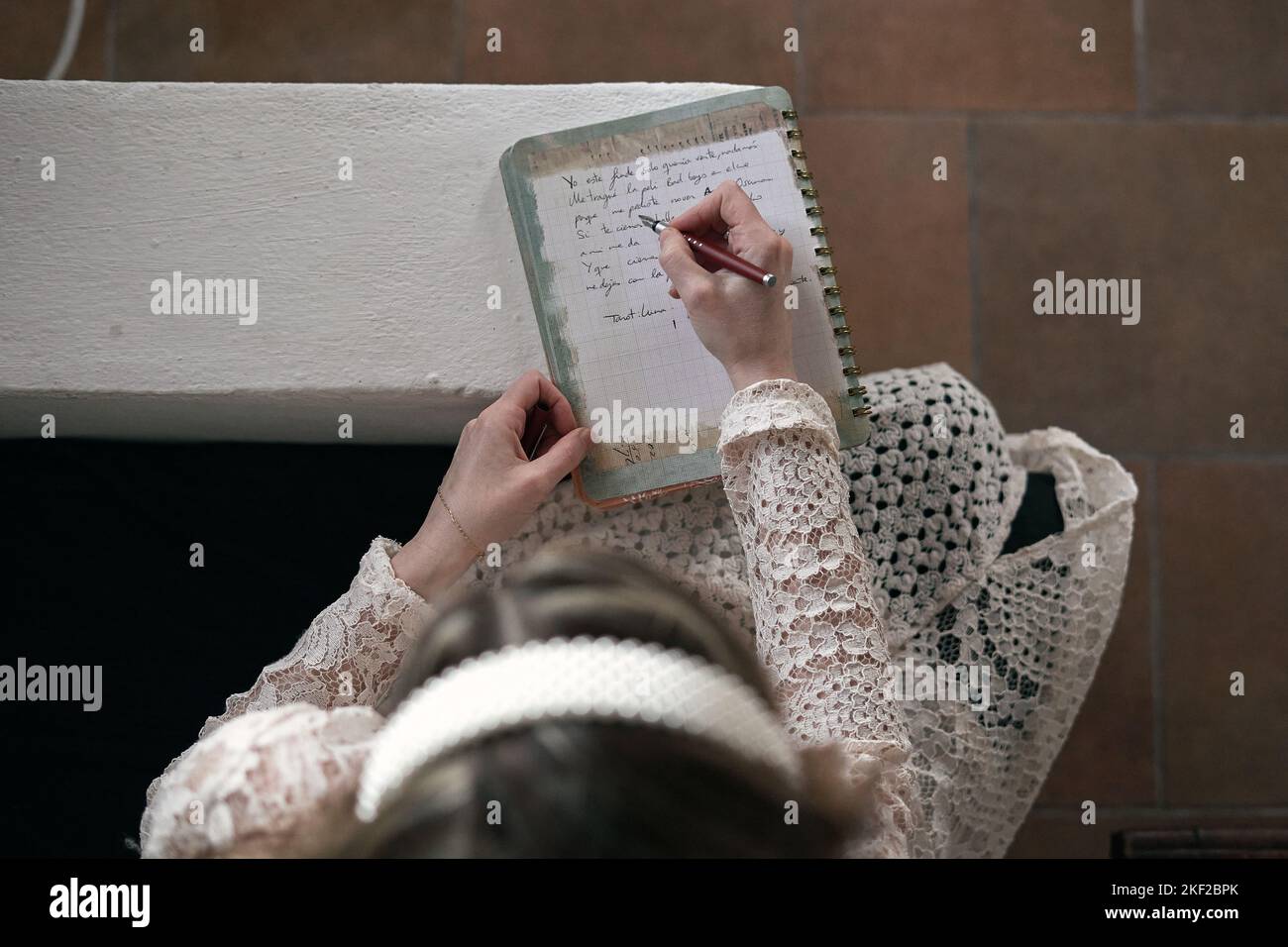 overhead shot of mature caucasian woman in white lace dress writing in ...