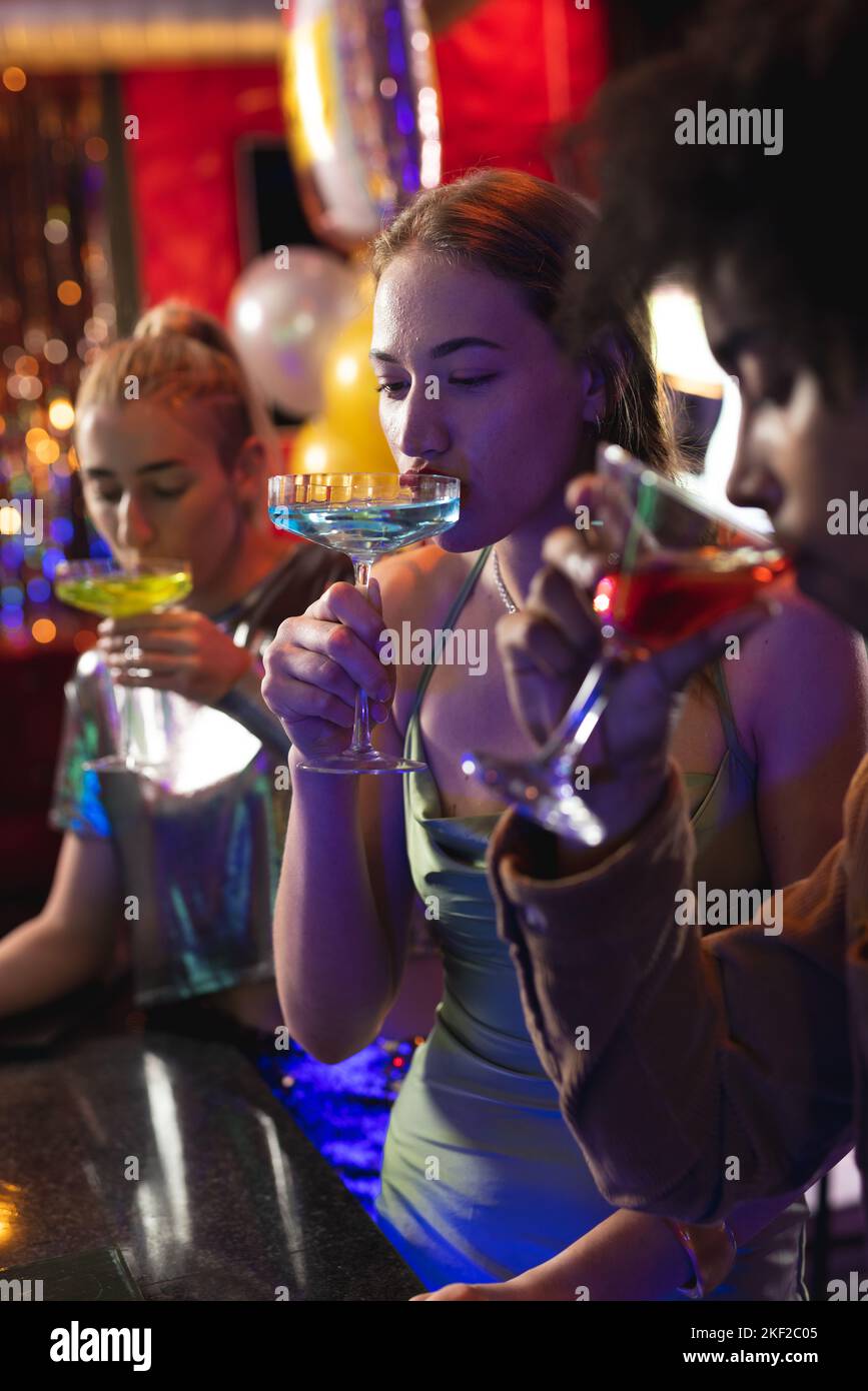 Vertical of three happy, diverse male and female friends drinking ...