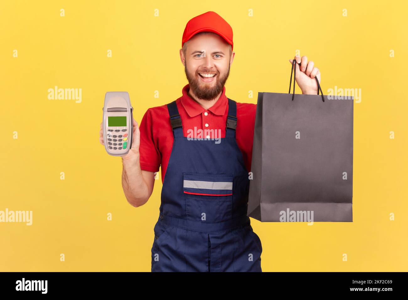 Portrait of happy satisfied delivery man standing with black shopping ...