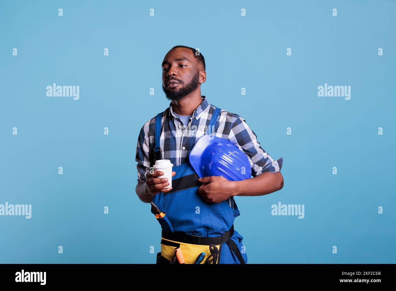 Tired construction worker drinking a cup of coffee at the end of his ...