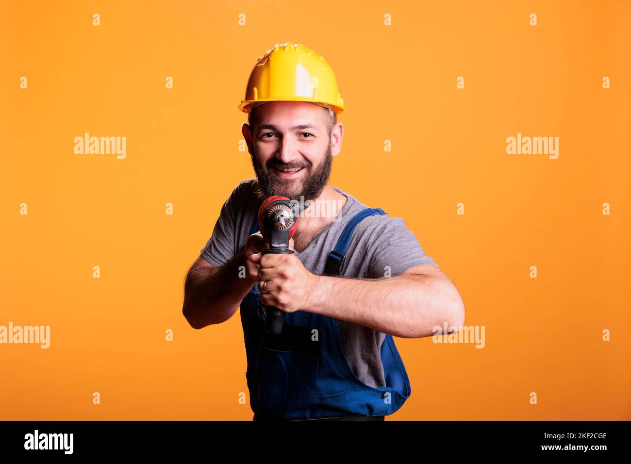 Cheerful construction worker holding power drill gun and posing in ...