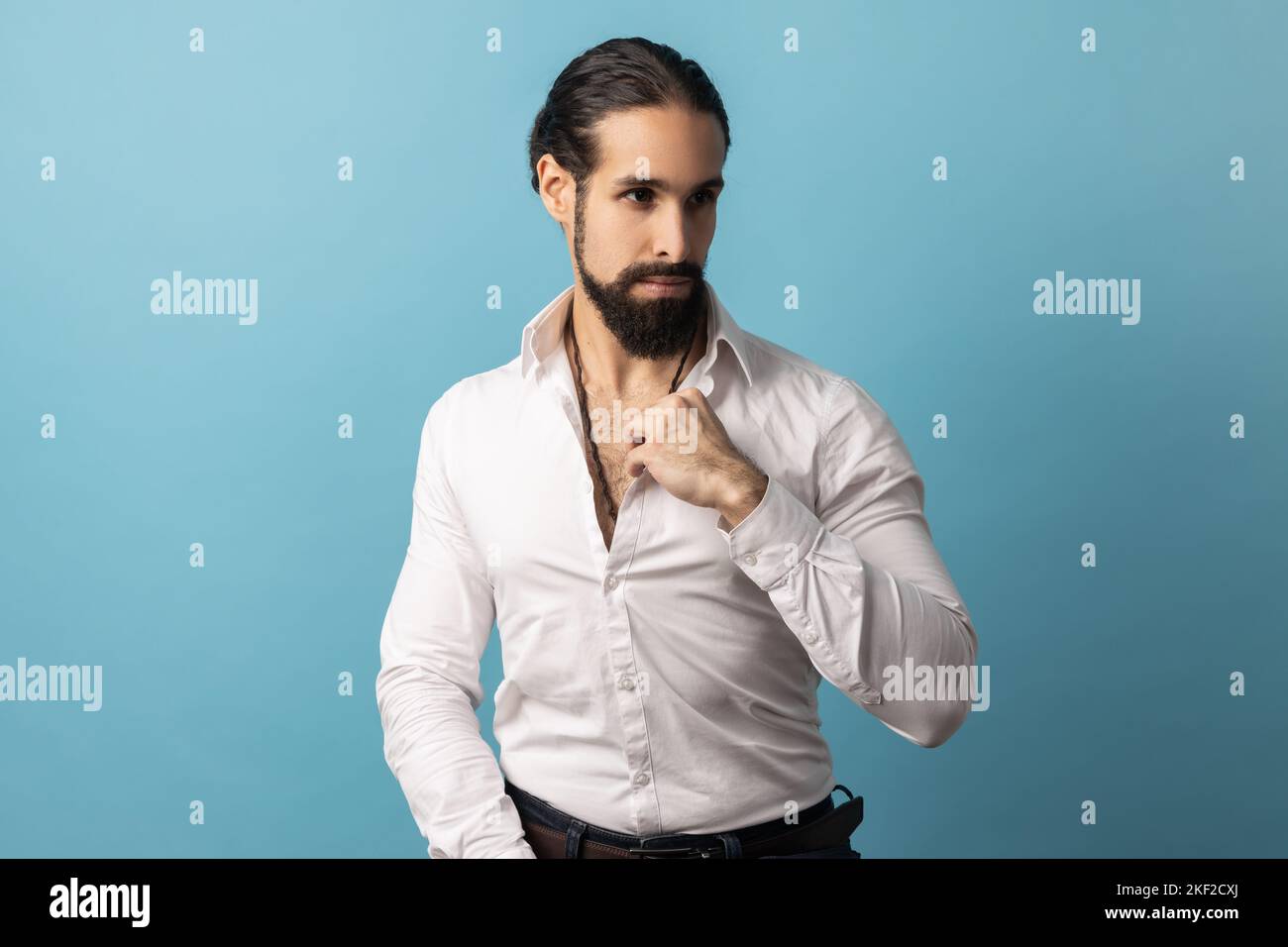 Portrait of serious handsome man with beard wearing white shirt looking ...