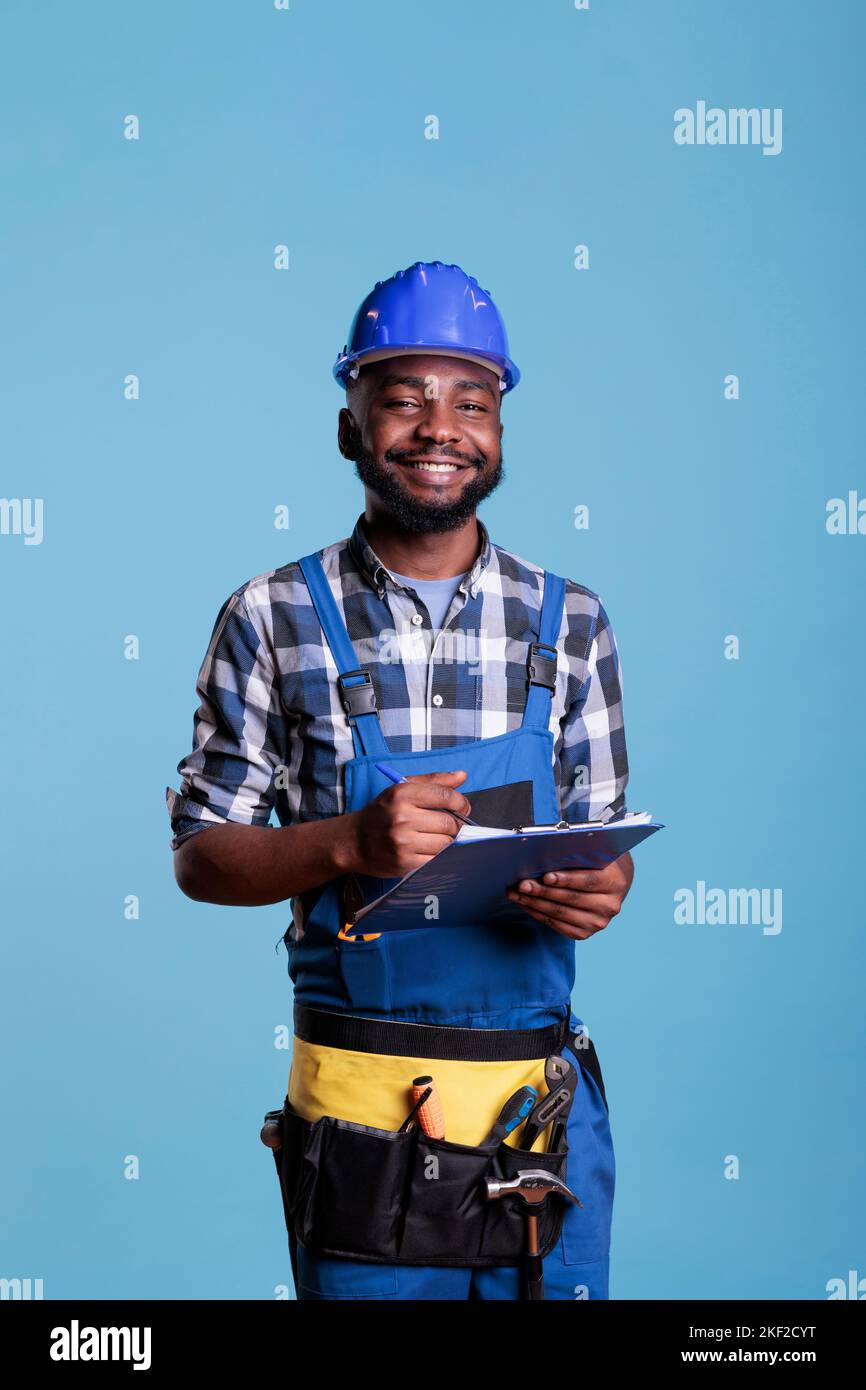 Portrait of construction contractor in hard hat and coveralls standing ...