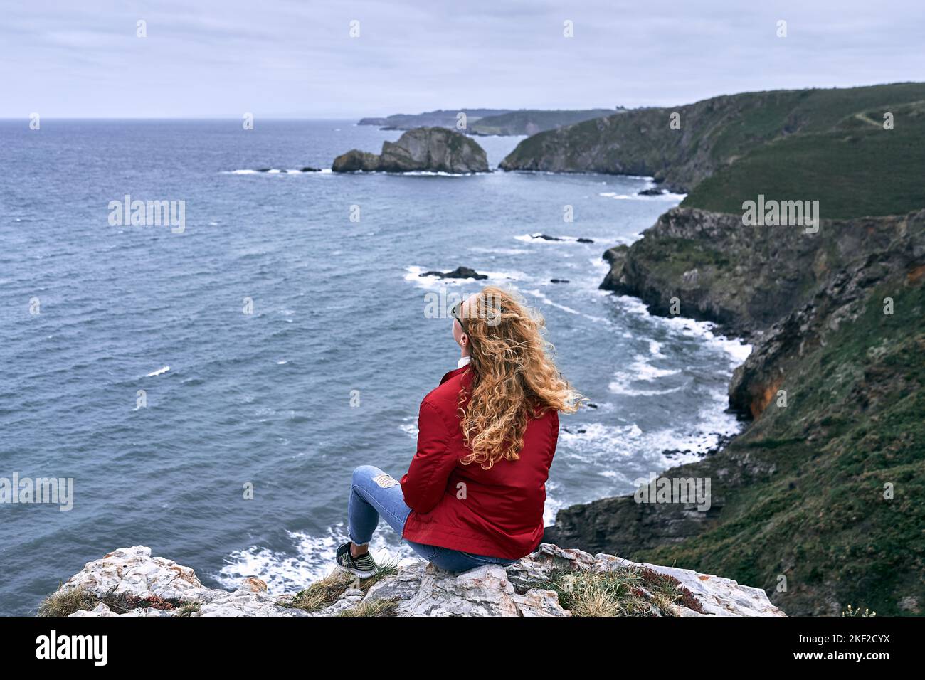 blond caucasian girl with red jacket and blue pants sneakers sitting on ...