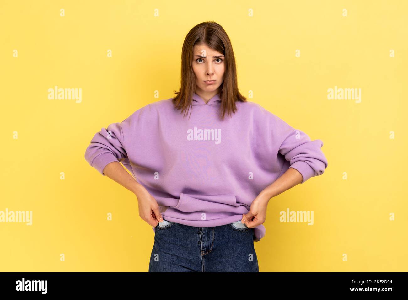 Unhappy poor woman turning empty pockets inside out and looking ...