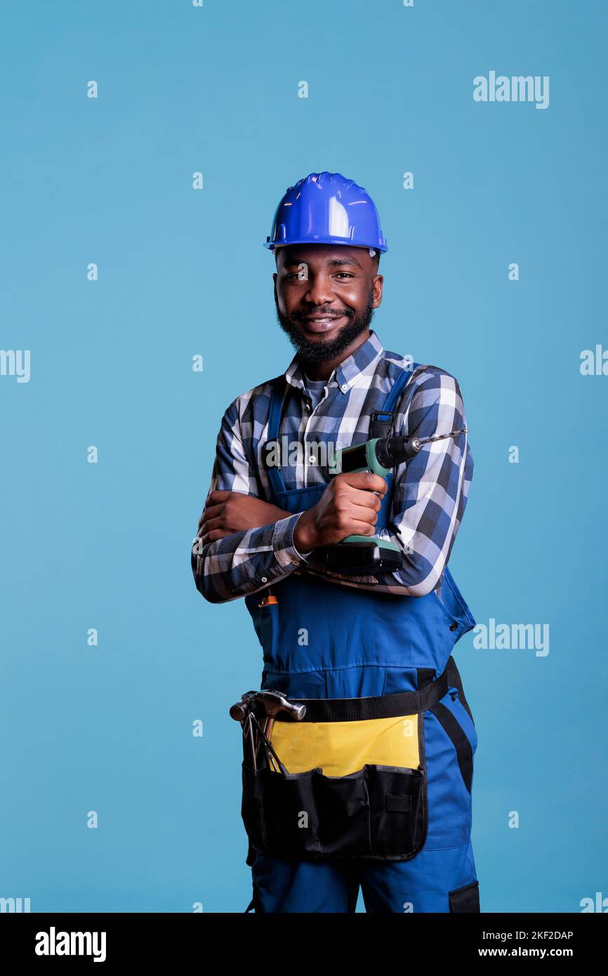 Professional contractor with hard hat and tool belt on light blue ...