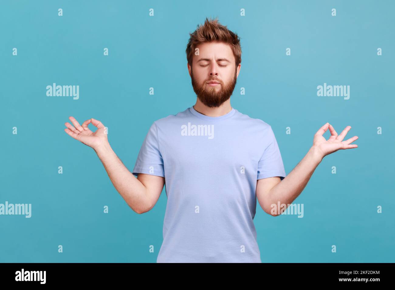 Portrait of calm man standing with raised arms and doing yoga ...
