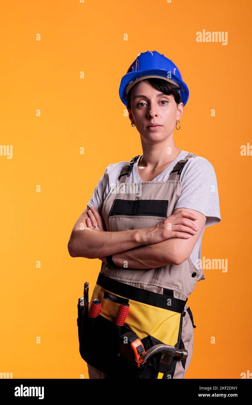 Portrait of female construction worker posing with arms crossed in ...