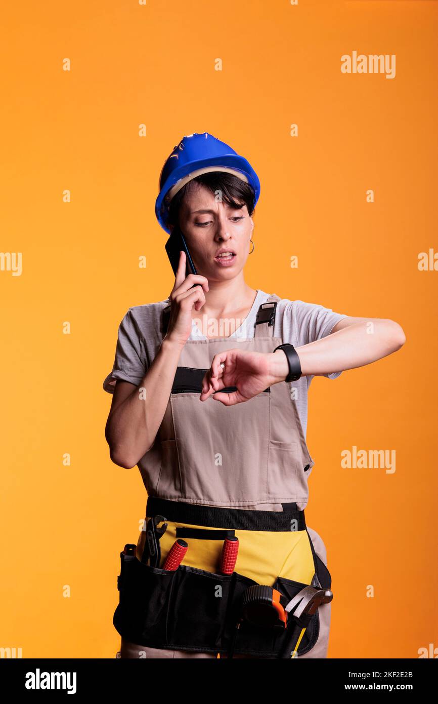 Building contractor checking time on wristwatch and talking on phone ...