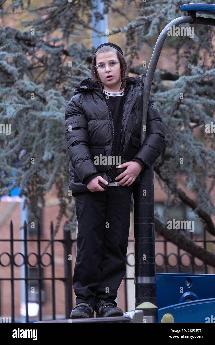 During recess at his yeshiva, an orthodox Jewish boy with peyot stands ...