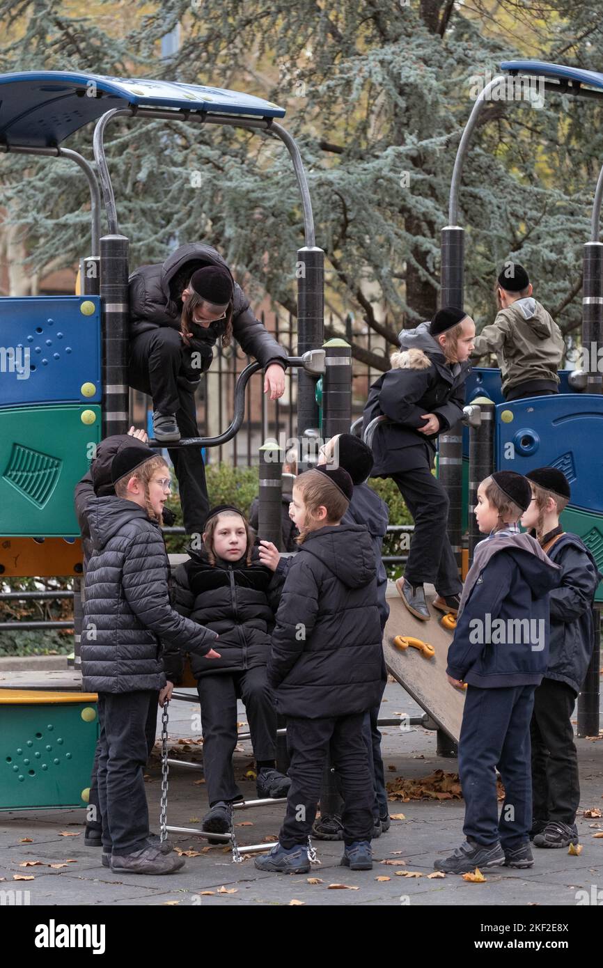 Playful orthodox Jewish children play on a sliding pond during recess ...