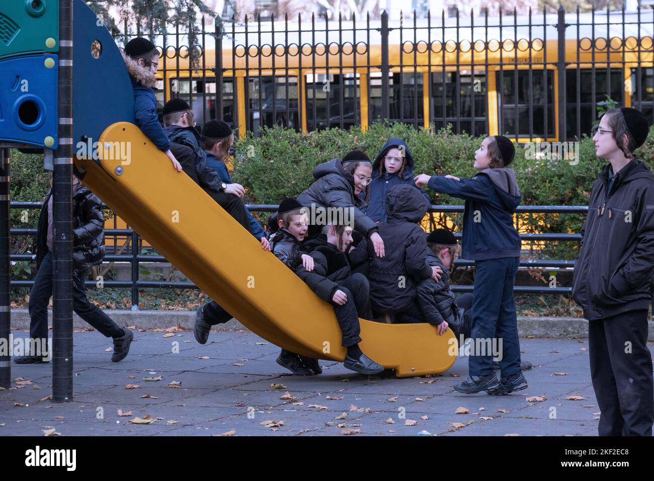 Playful orthodox Jewish children play on a sliding pond during recess ...