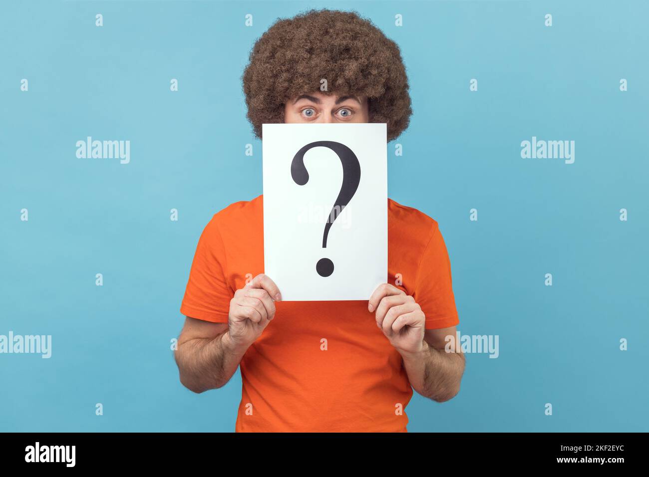 Man with Afro hairstyle in orange T-shirt hiding half of face behind ...