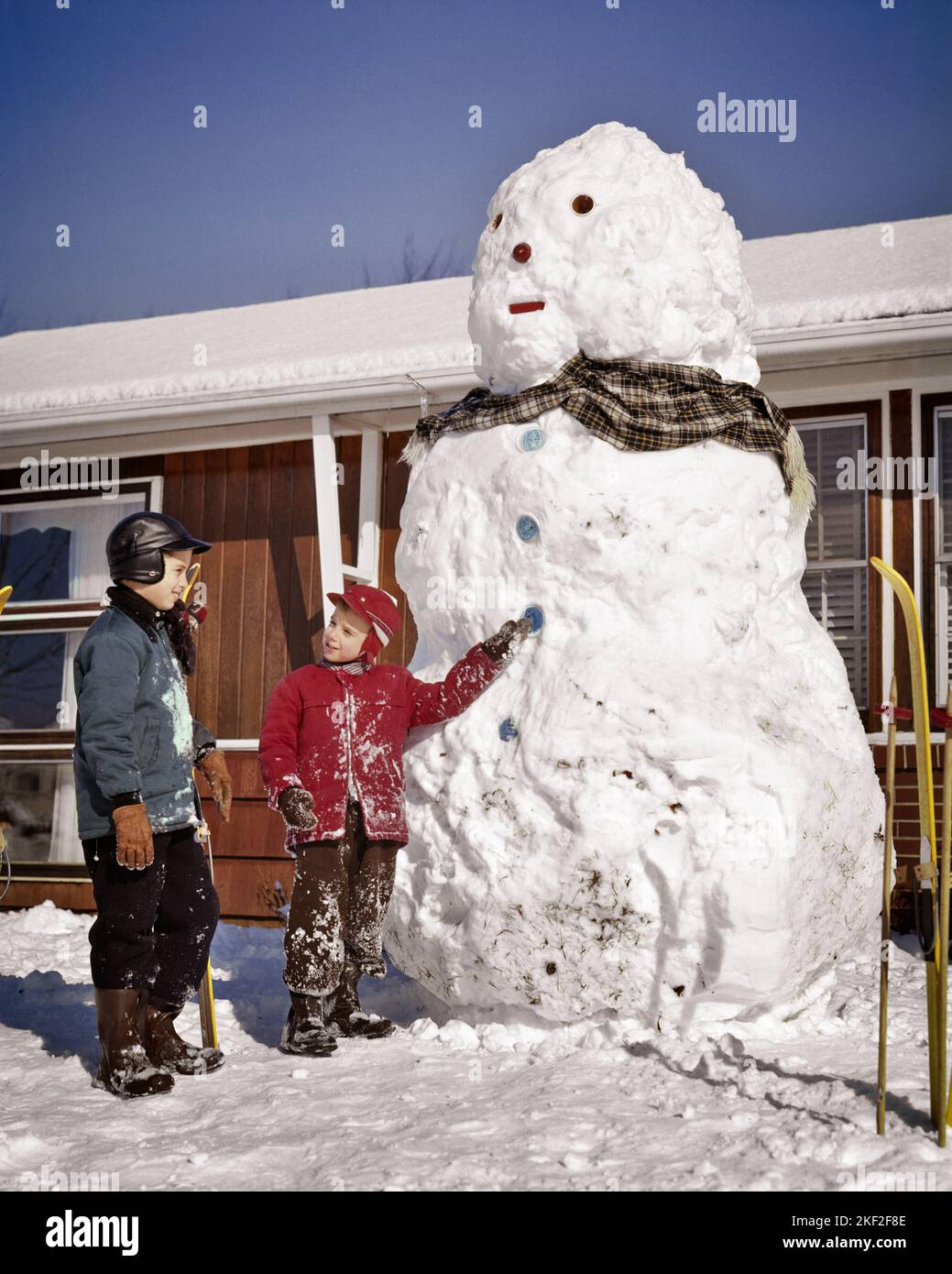 1960s TWO BOYS BROTHERS BUILDING TALL GIANT SNOWMAN IN FRONT OF ...